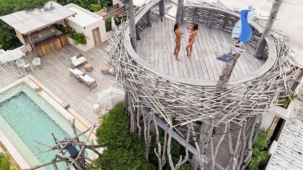 Um deck circular de madeira com piscina, espreguiçadeiras e guarda-sóis.