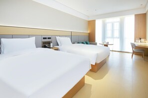 Quarto de hotel com duas camas, uma escrivaninha e uma cadeira.