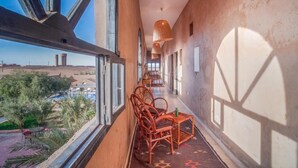 Corredor com vista para paisagem desértica, uma mesa com cadeiras e um lustre.