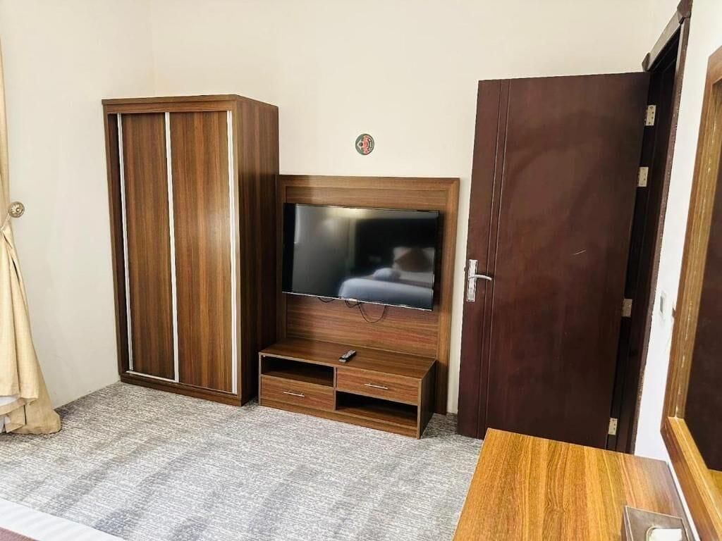 Quarto com aparador de madeira, televisão e guarda-roupa.