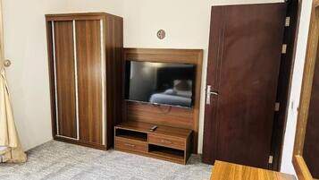 Quarto com aparador de madeira, televisão e guarda-roupa.