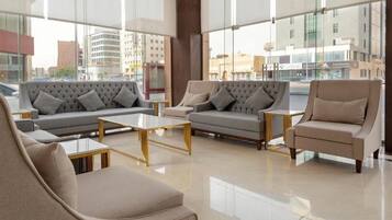 Um hall de hotel moderno com um conjunto de sofás, mesa de centro e poltronas.