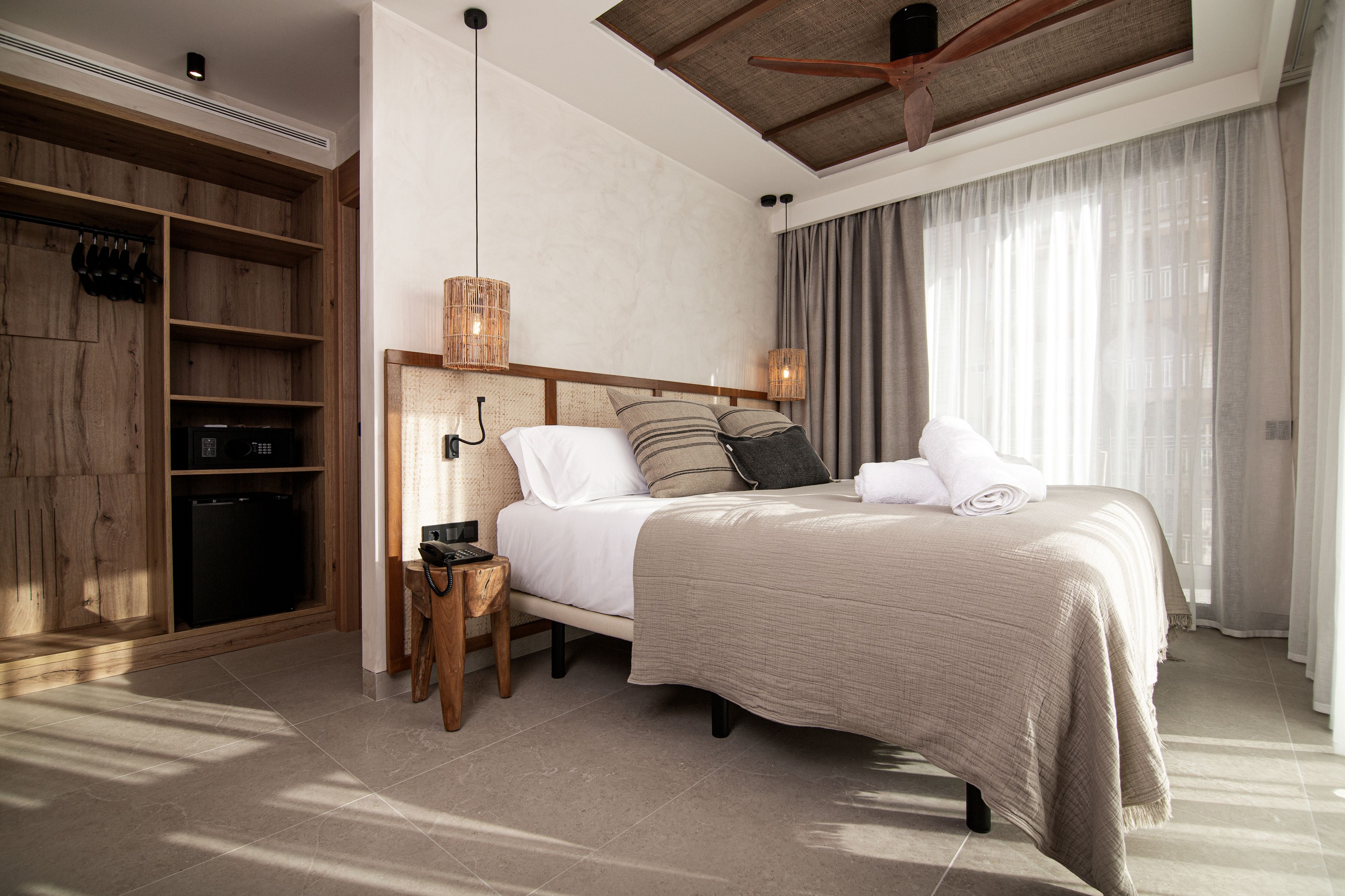 Quarto com cama, guarda-roupa de madeira e uma pequena mesa.