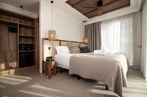 Quarto com cama, guarda-roupa de madeira e uma pequena mesa.