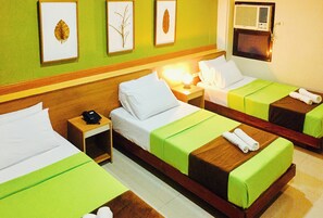 Quarto de hotel com duas camas de solteiro, uma mesa de cabeceira com telefone e um ar condicionado fixado na parede.