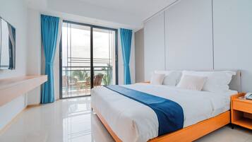 Quarto de hotel moderno com uma cama grande, uma mesa de cabeceira, uma televisão e uma varanda com cortinas azuis.