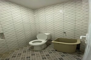 Casa de banho com sanita, banheira e paredes em azulejo.