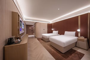 Quarto de hotel com duas camas, uma escrivaninha e uma televisão.