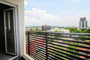 Uma varanda com vista para a paisagem urbana, incluindo edifícios e áreas verdes.