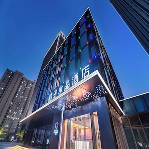 Um edifício moderno de hotel com letreiros iluminados e fachada de vidro.