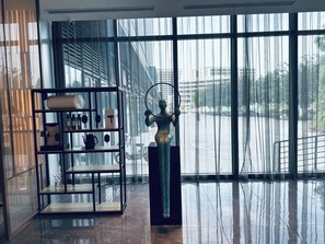 Um interior moderno com piso de mármore, uma vitrine de vidro com objetos e uma estátua.