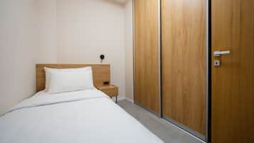 Quarto com cama, guarda-roupa de madeira e mesa de cabeceira.