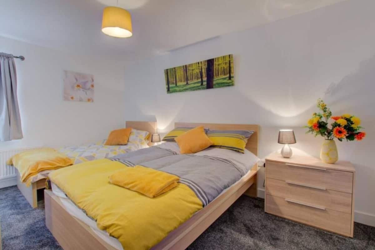 Quarto com cama, mesas de cabeceira, abajur e um quadro na parede.