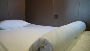 Cama com roupa de cama branca e um cobertor bem dobrado.