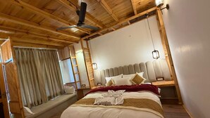 Quarto com cama, mesa de cabeceira, ventoinha no teto e janela com cortinas.