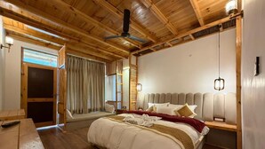 Quarto com painéis de madeira, uma cama, uma escrivaninha e uma janela com cortinas.