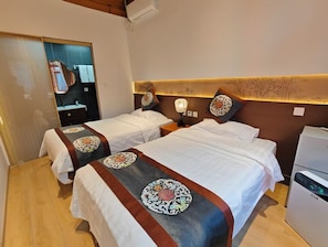 Quarto de hotel com duas camas, um espelho, mesa de cabeceira com abajur, aquecedor e guarda-roupa.