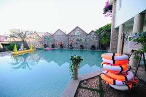 Piscina com boias, muro de tijolos com murais e placa indicativa do Veranda Beach Resort.