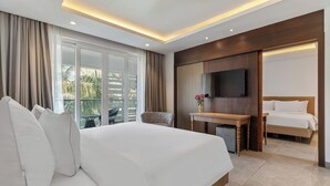 Quarto de hotel com uma cama grande, uma escrivaninha com televisão de tela plana e uma varanda com cortinas.