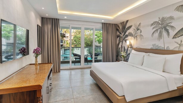 Quarto de hotel moderno com uma cama grande, uma escrivaninha, vista para a piscina exterior e uma varanda.