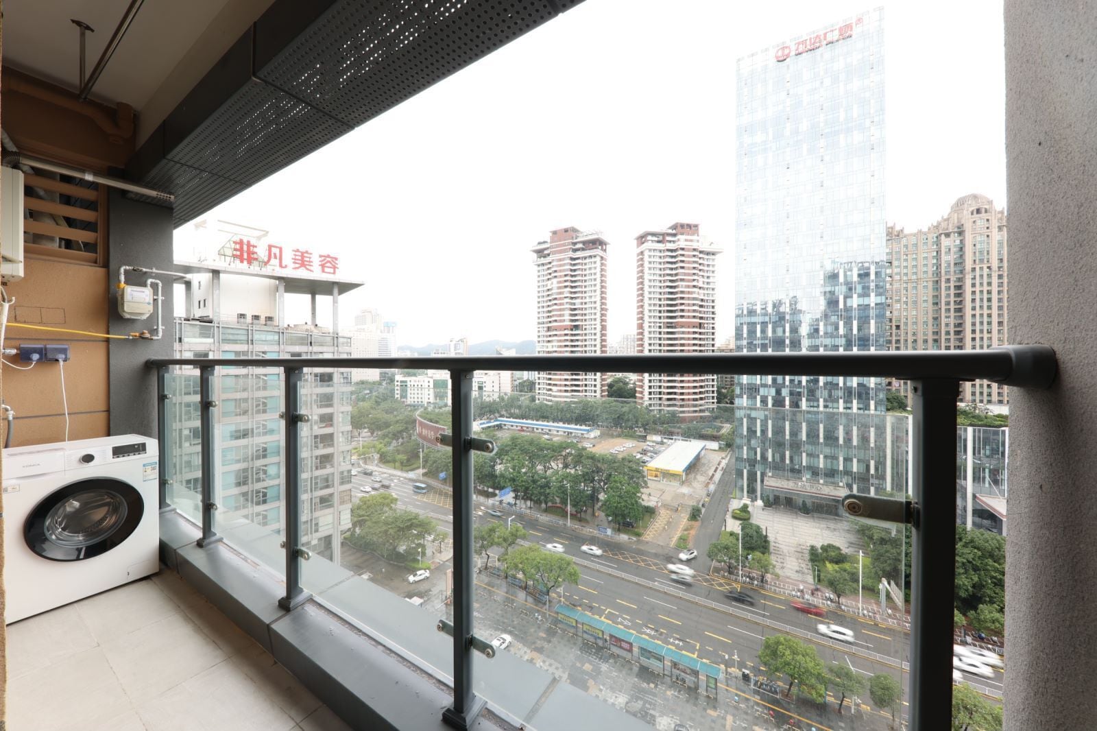 Varanda com máquina de lavar, vista para um horizonte urbano com edifícios altos e céu claro.