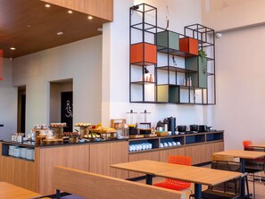 Um café moderno com mobiliário de madeira, um balcão com diversos produtos alimentícios e uma estante geométrica peculiar.
