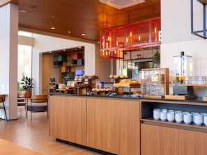 Um café moderno com balcões de madeira, máquina de café e diversos produtos de pastelaria.