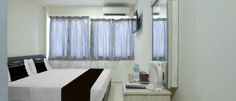 Quarto com cama, mesa de cabeceira com controle remoto, espelho e ar condicionado.