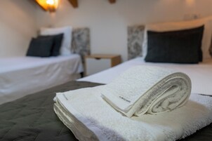 Quarto de hotel com duas camas, uma mesa de cabeceira e uma luminária fixada na parede.