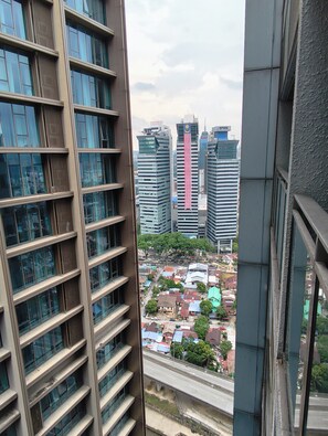 Um edifício alto com vários andares e grandes janelas, com vista para uma paisagem urbana com diversos edifícios e uma autoestrada.