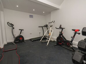 Uma academia com equipamentos de exercícios, incluindo bicicleta ergométrica, elíptico e esteira.