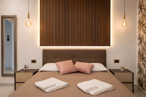 Quarto moderno com uma cama grande, duas mesas de cabeceira e um painel de luz fixado na parede.
