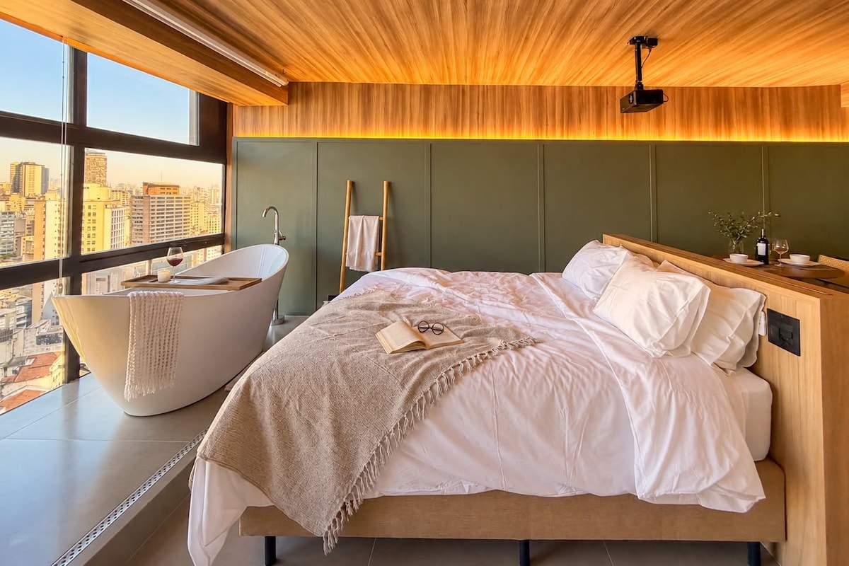 Quarto moderno com cama grande, banheira e vista para a cidade.