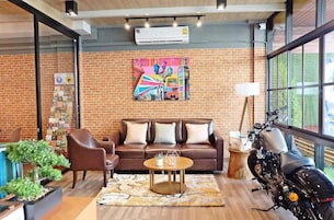 Interior moderno com parede de tijolos, um sofá, mesa de centro e uma motocicleta, além de uma janela grande.