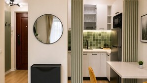 Uma cozinha compacta com área de refeições, um sofá preto e um espelho.