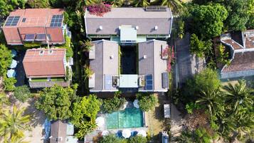 Vista aérea de um bairro residencial com várias casas, uma piscina e vegetação exuberante.