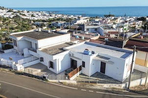 Zona residencial com edifícios brancos, uma estrada e vista para o mar.