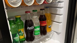 Uma geladeira com diversas bebidas, incluindo latas e garrafas de refrigerante.