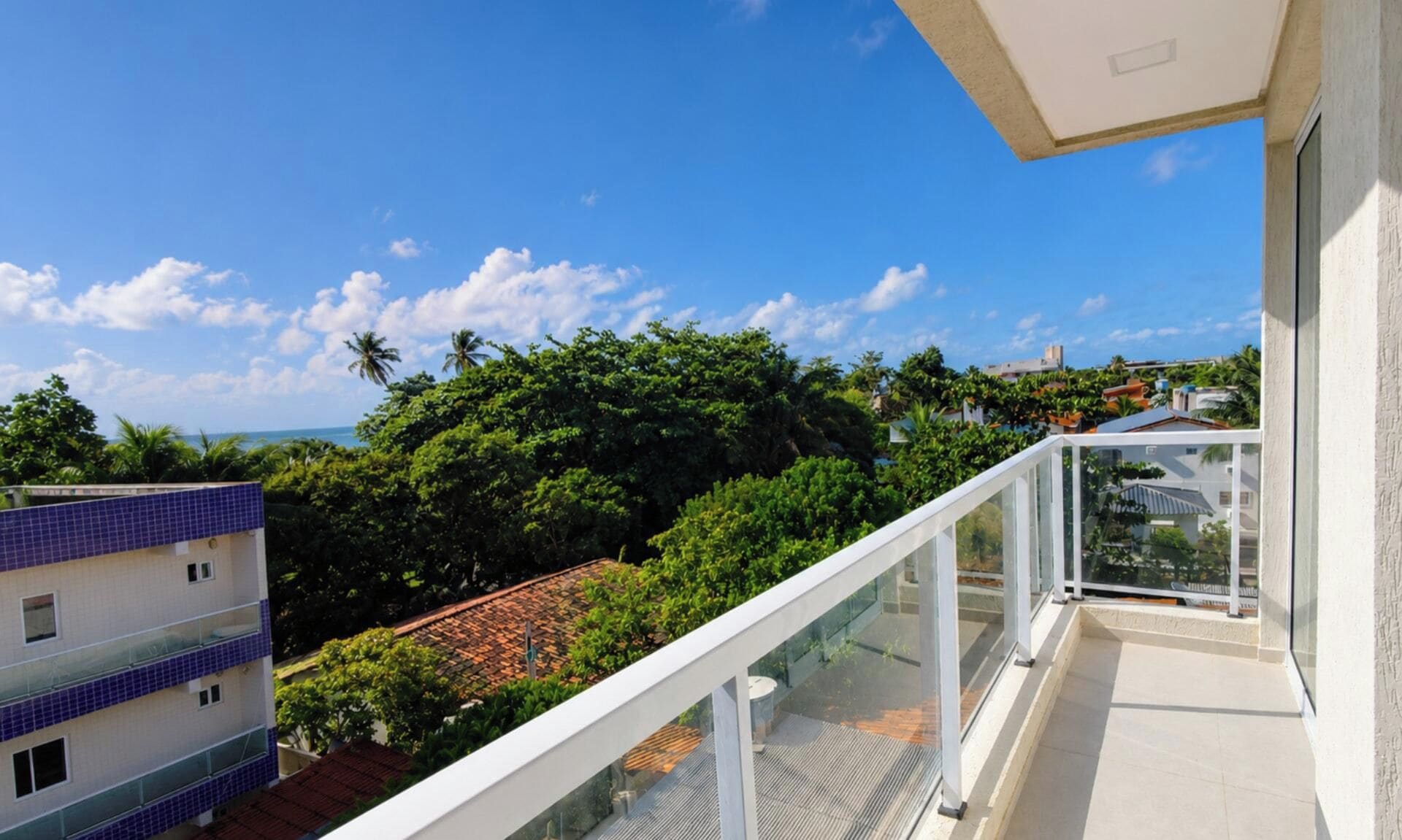 Varanda com vista desobstruída para uma paisagem tropical, incluindo árvores e um corpo d'água ao longe.