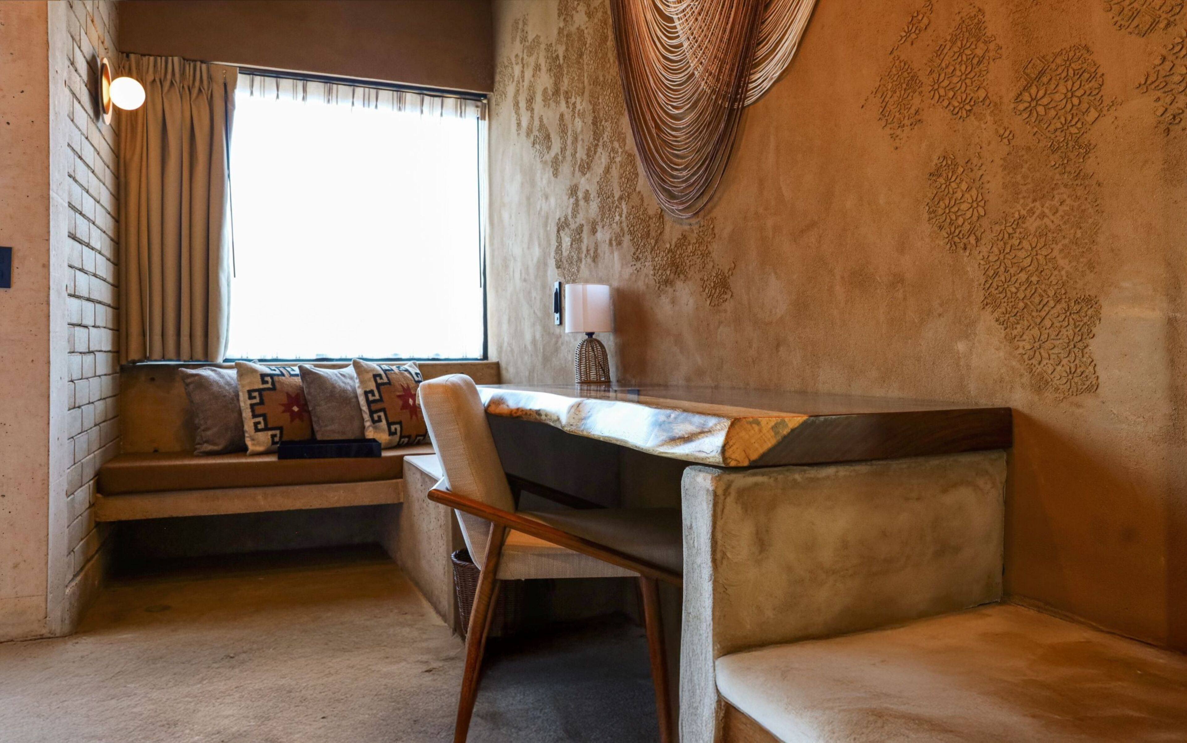Um espaço aconchegante com um banco, uma cadeira e uma mesa.