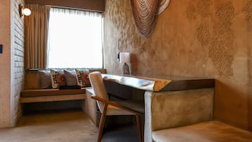 Um espaço aconchegante com um banco, uma cadeira e uma mesa.