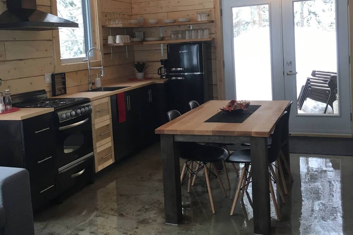 Interior em madeira com cozinha, área de refeições e uma janela grande.
