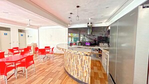 Cozinha moderna com bancada de mármore, eletrodomésticos de aço inoxidável e cadeiras vermelhas.