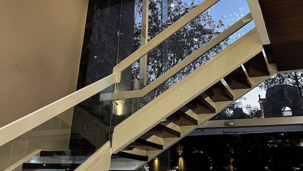 Um interior moderno com uma escada, um candelabro e janelas amplas.