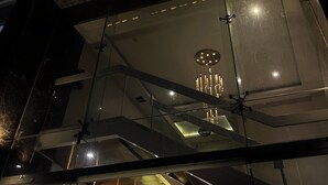 Um hotel com fachada moderna, um letreiro iluminado em destaque e uma escadaria visível que leva à entrada.