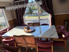 Uma sala de jantar com uma mesa de mármore, cadeiras estofadas em vermelho e um candelabro.