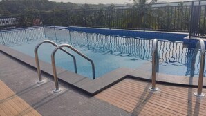 Uma piscina com guarda-corpos de metal, rodeada por um deck de madeira.