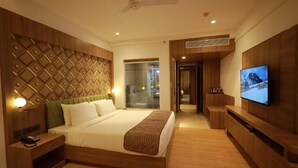 Quarto de hotel com cama, mesa de cabeceira, televisão e vista exterior.