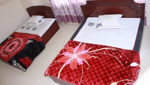 Duas camas com cabeceiras, uma janela com cortinas e um chão de azulejos.