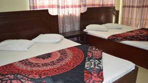 Quarto de hotel com duas camas, cada uma com cabeceira de madeira e roupa de cama branca.